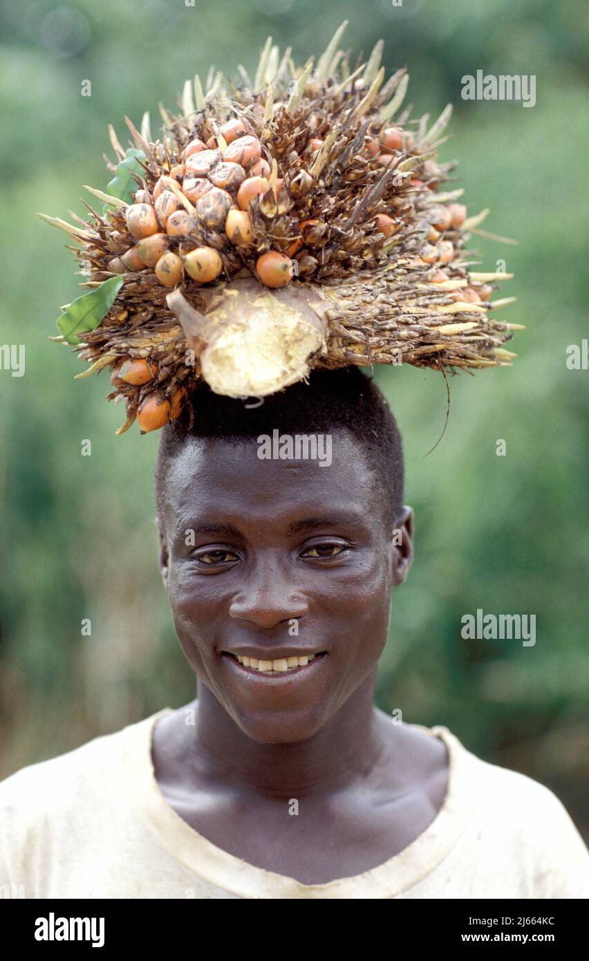 Ghana, Kumasi region; Portrait of a man carrying harvested palm seeds ...