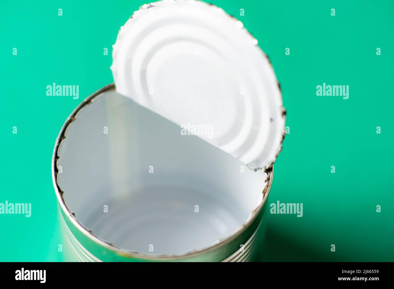 Open empty tin can on a green background Stock Photo - Alamy