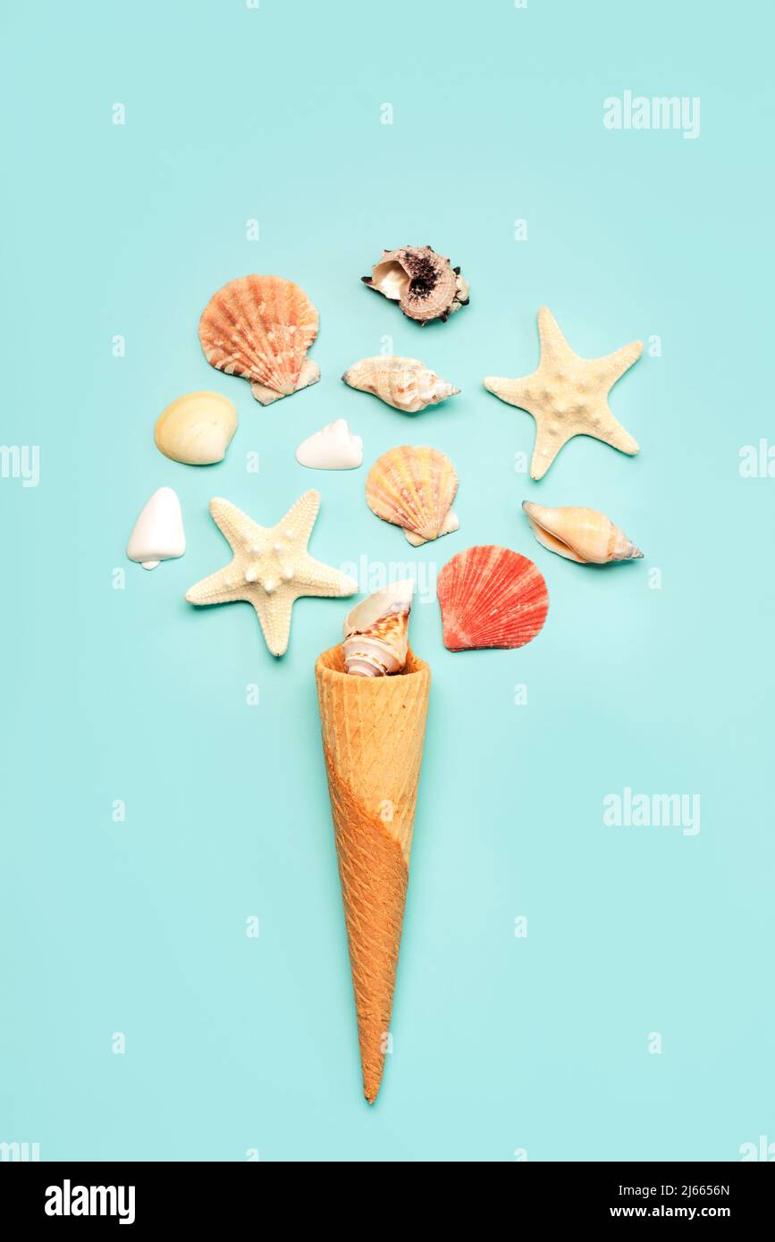 Ice cream cone with sea shells and starfish over blue background ...