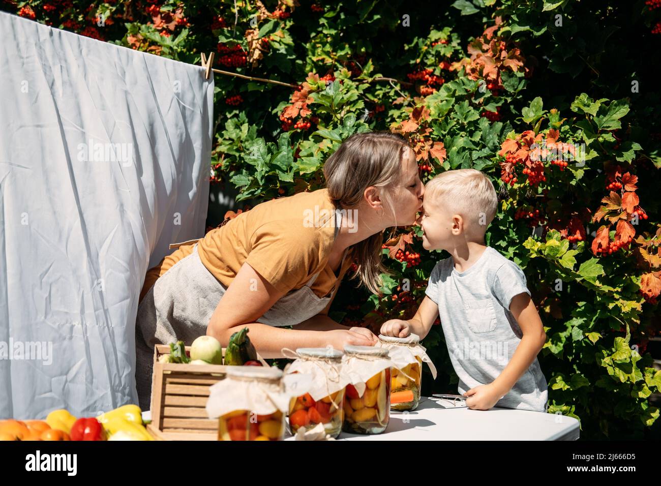 Happy family mother and son kid canning vegetables in the garden in ...