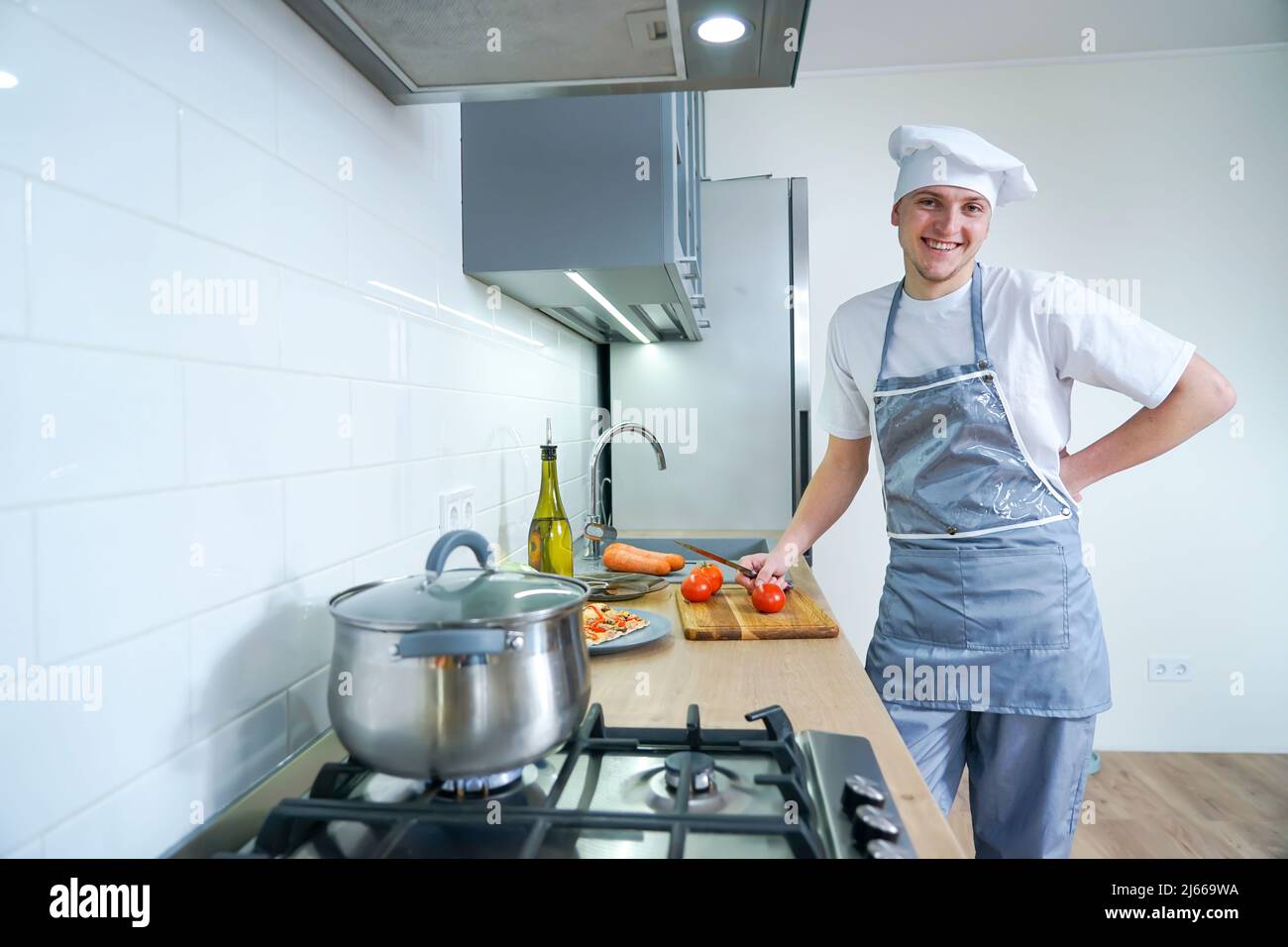 Portrait of a professional chef in the kitchen. He is wearing a white ...