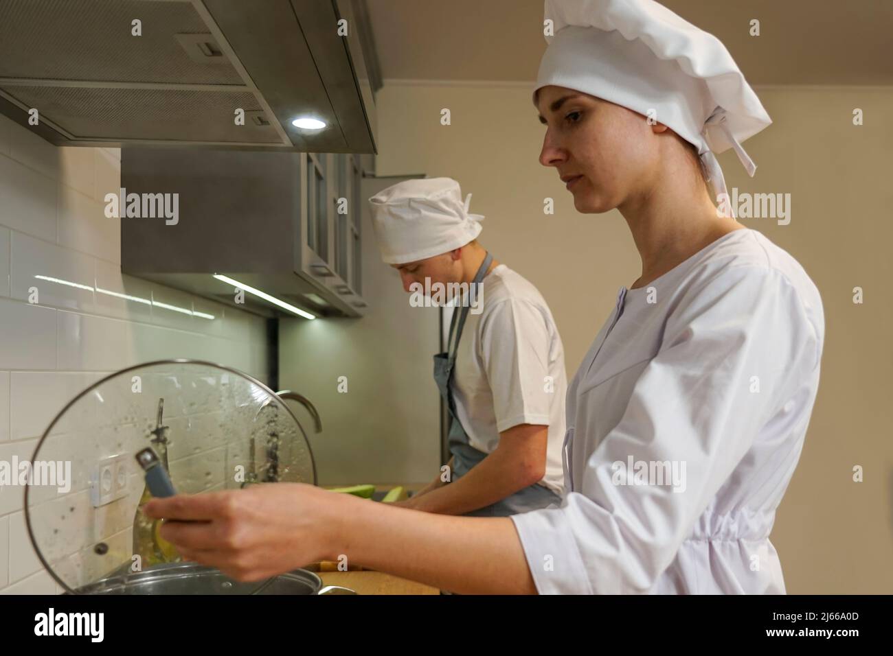 Chefs in the restaurant kitchen prepare food. The chef is dressed in a ...