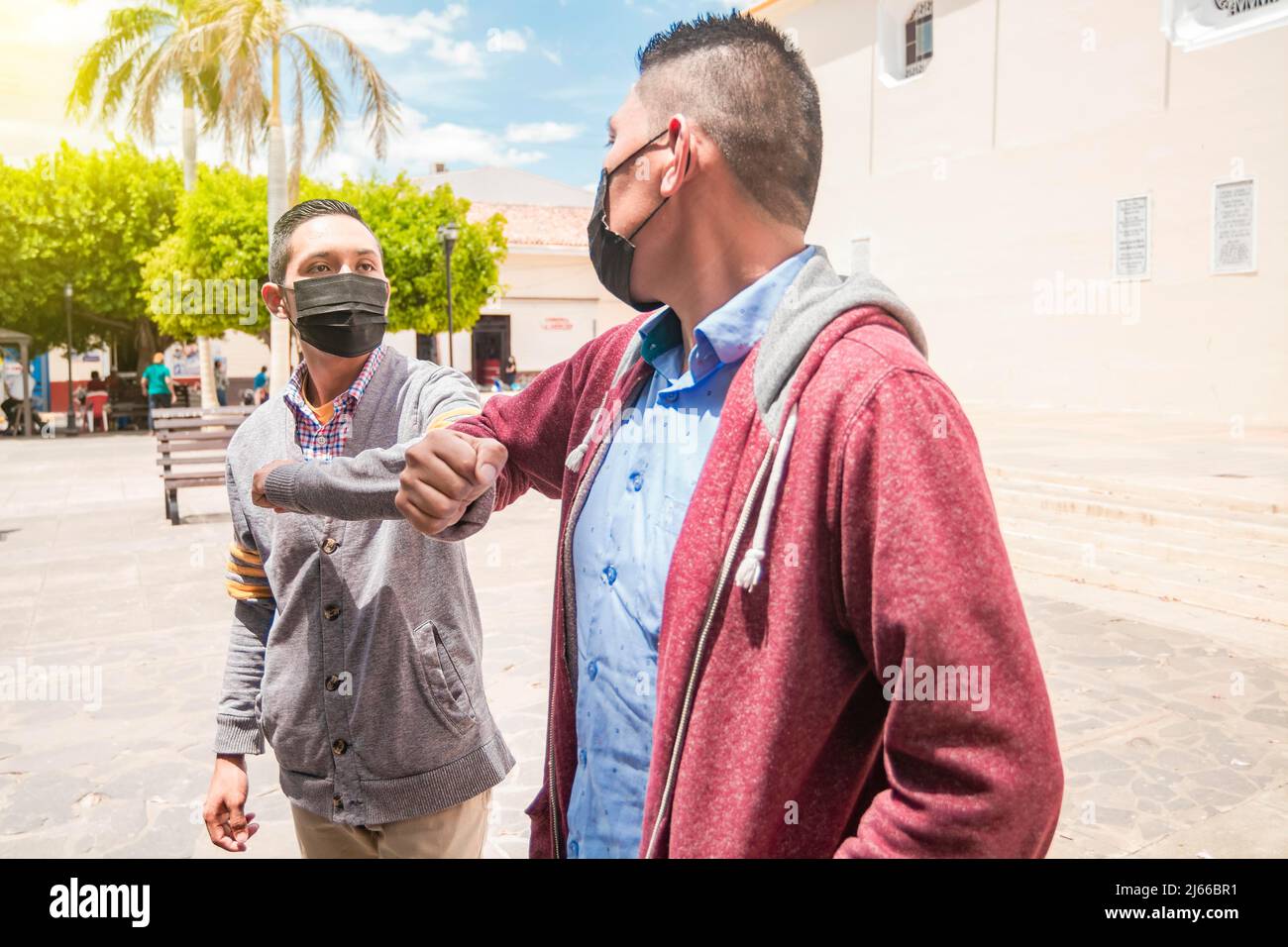 Two guys shaking elbows, two men wearing face masks shaking elbows ...