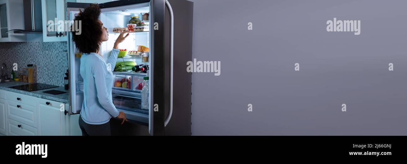 Side View Of Young African Woman Searching Food In An Open Refrigerator ...