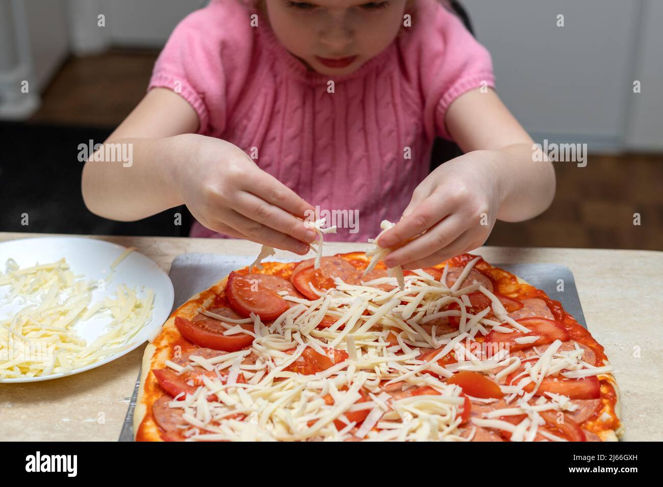 Small child cooking at home sitting at the table. Little girl making ...
