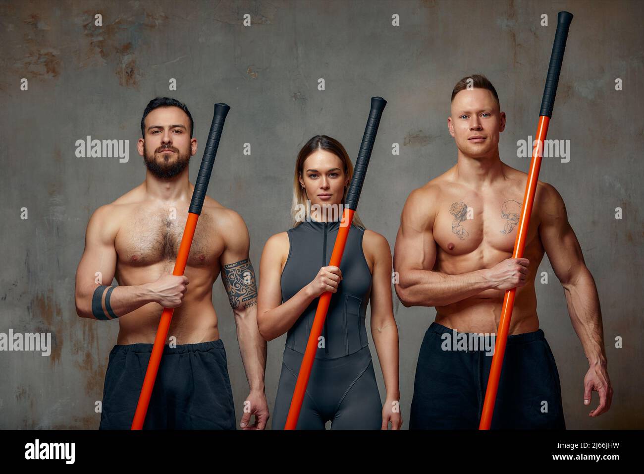Two men and woman aikido fighters with wooden fight stick posing in ...