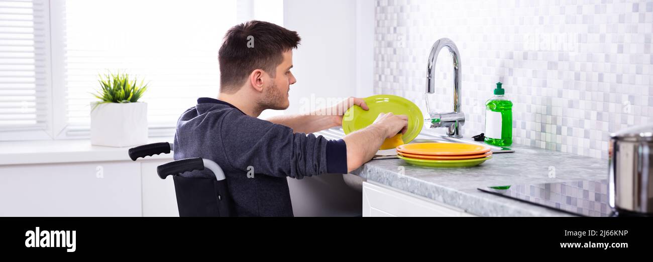 Handicapped Man Sitting On Wheelchair Washing And Cleaning Dishes In ...