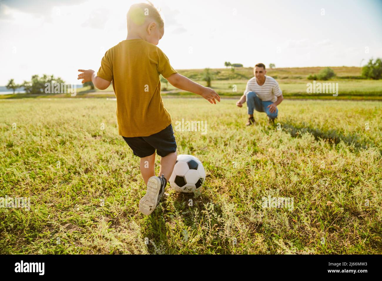 Young white father and his little son playing football together ...