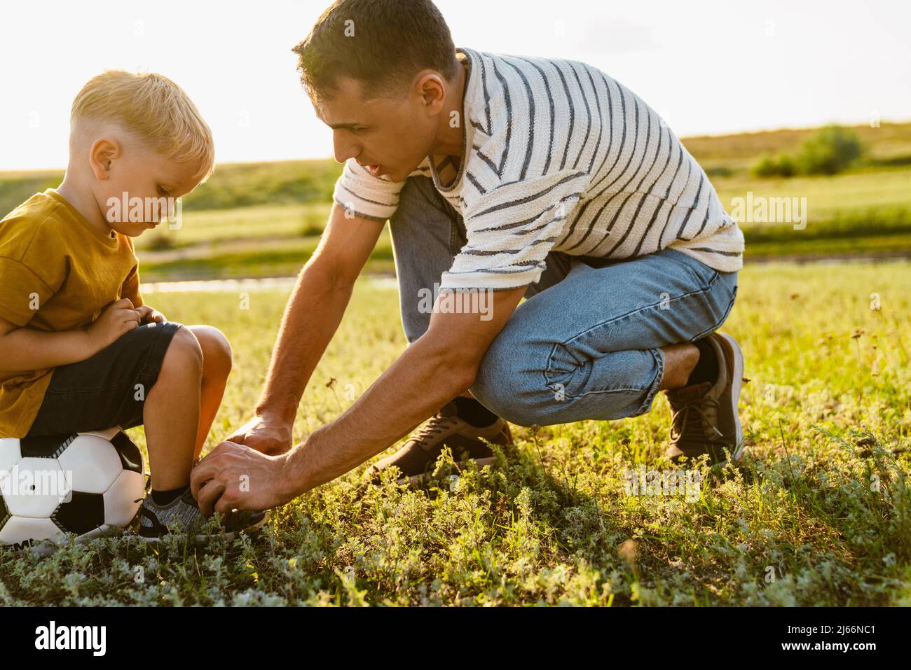 Young white father talking with her sad son while squatting on summer ...