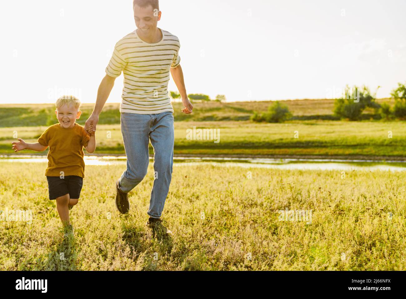 Young white father with his little son holding hands while running ...