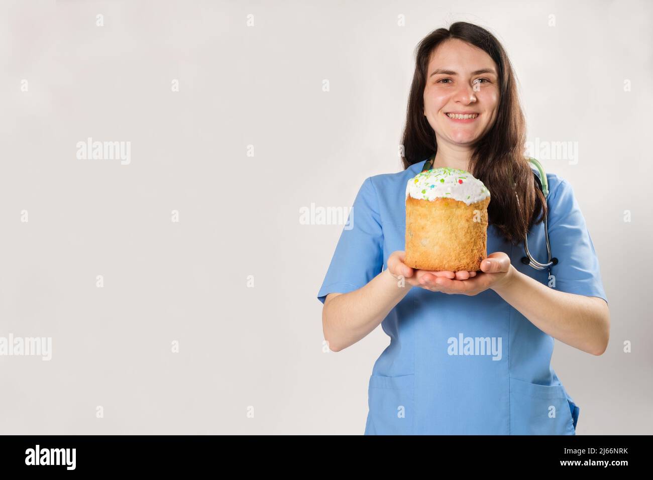 The doctor holds an Easter cake and smiles, a place for text. Medical ...