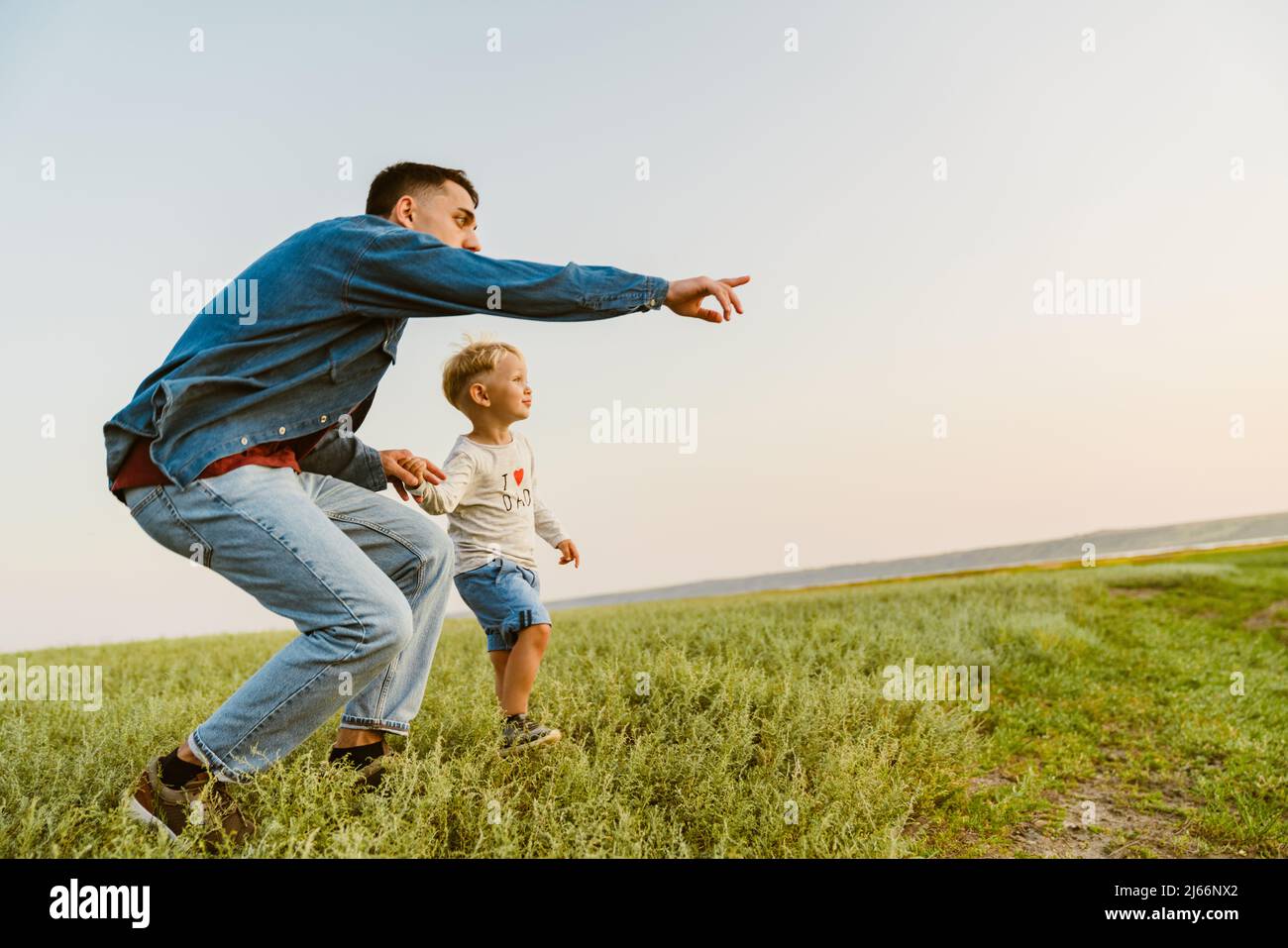 Young white father pointing finger aside while standing with his son on ...