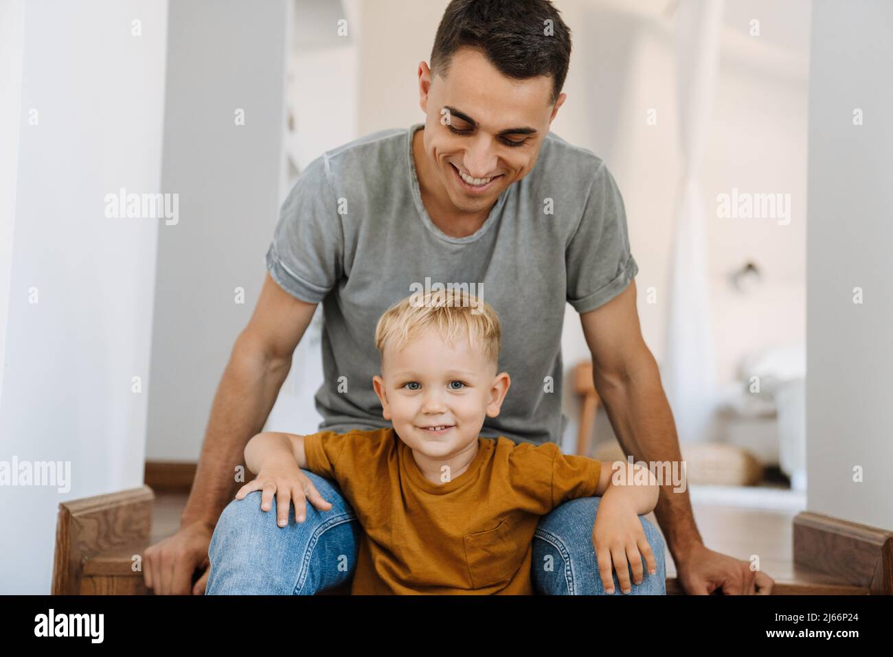 Young white father smiling while sitting with his son on stairs at home ...
