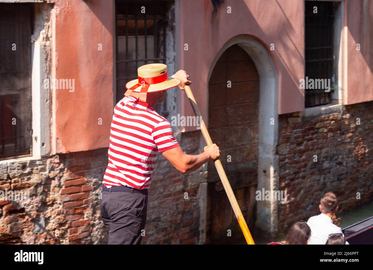 A Venetian gondolier in a traditional black gondola floats down a ...
