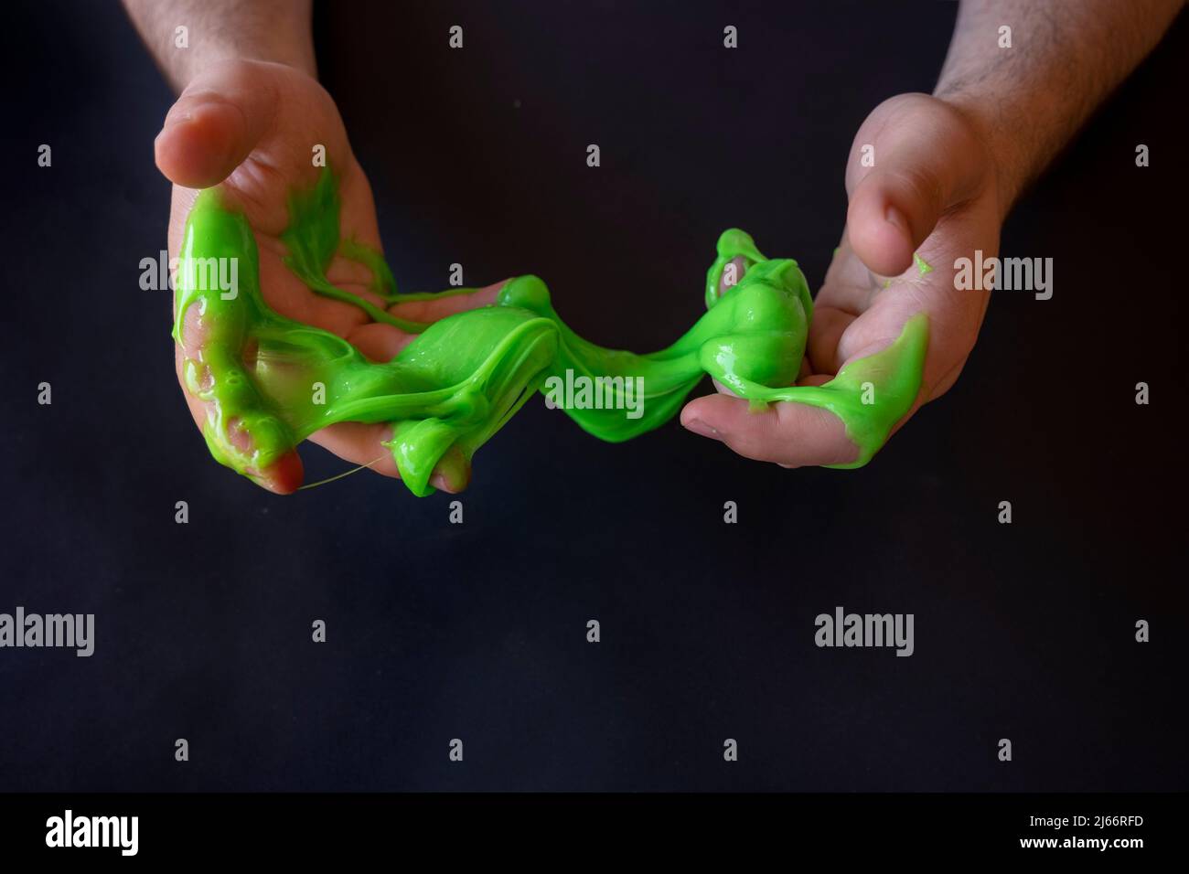 Green slime toy on man hand, struggling and playing with glitter green ...