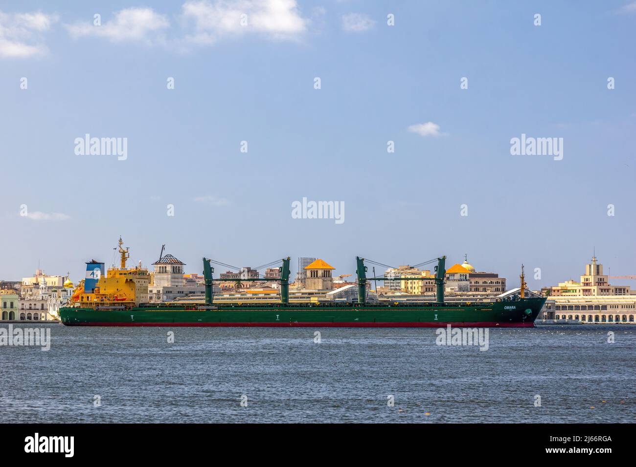 A freight or cargo ship is in the bay or port of the capital city. The ...