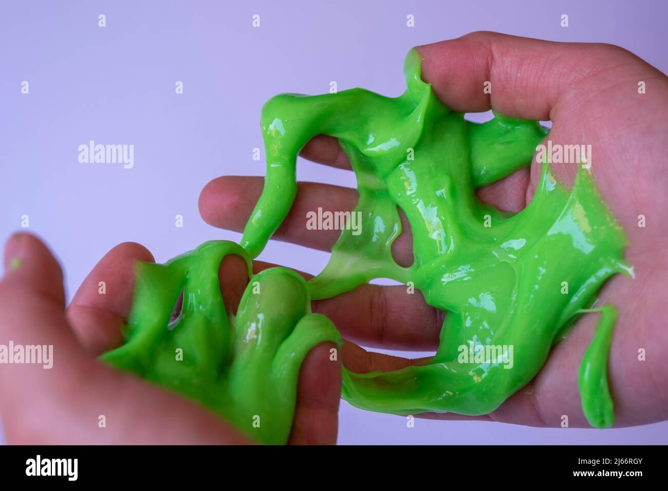 Green slime toy on man hand, struggling and playing with glitter green ...