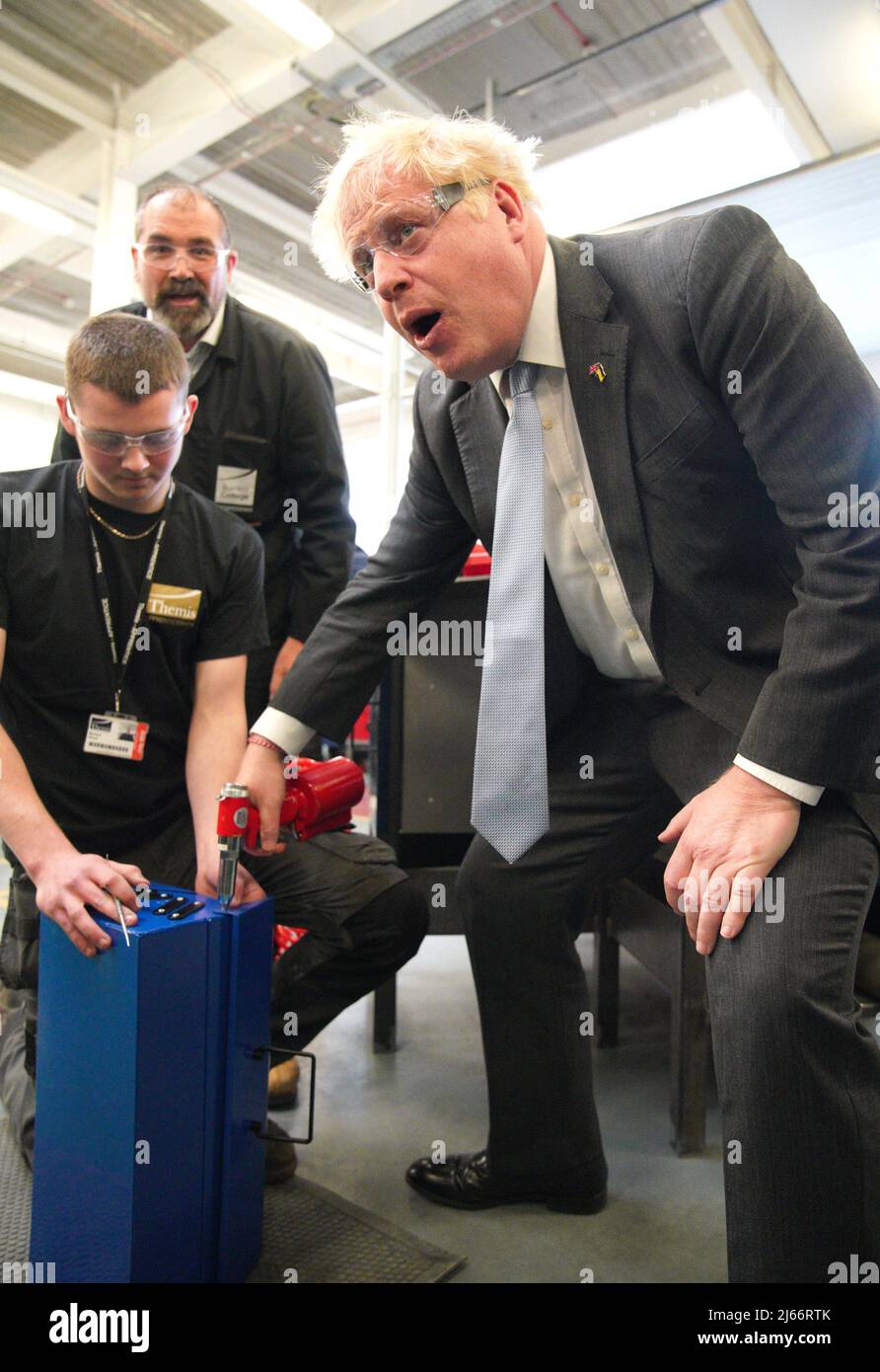 Prime Minister Boris Johnson uses a rivet gun to fire a rivet into a ...