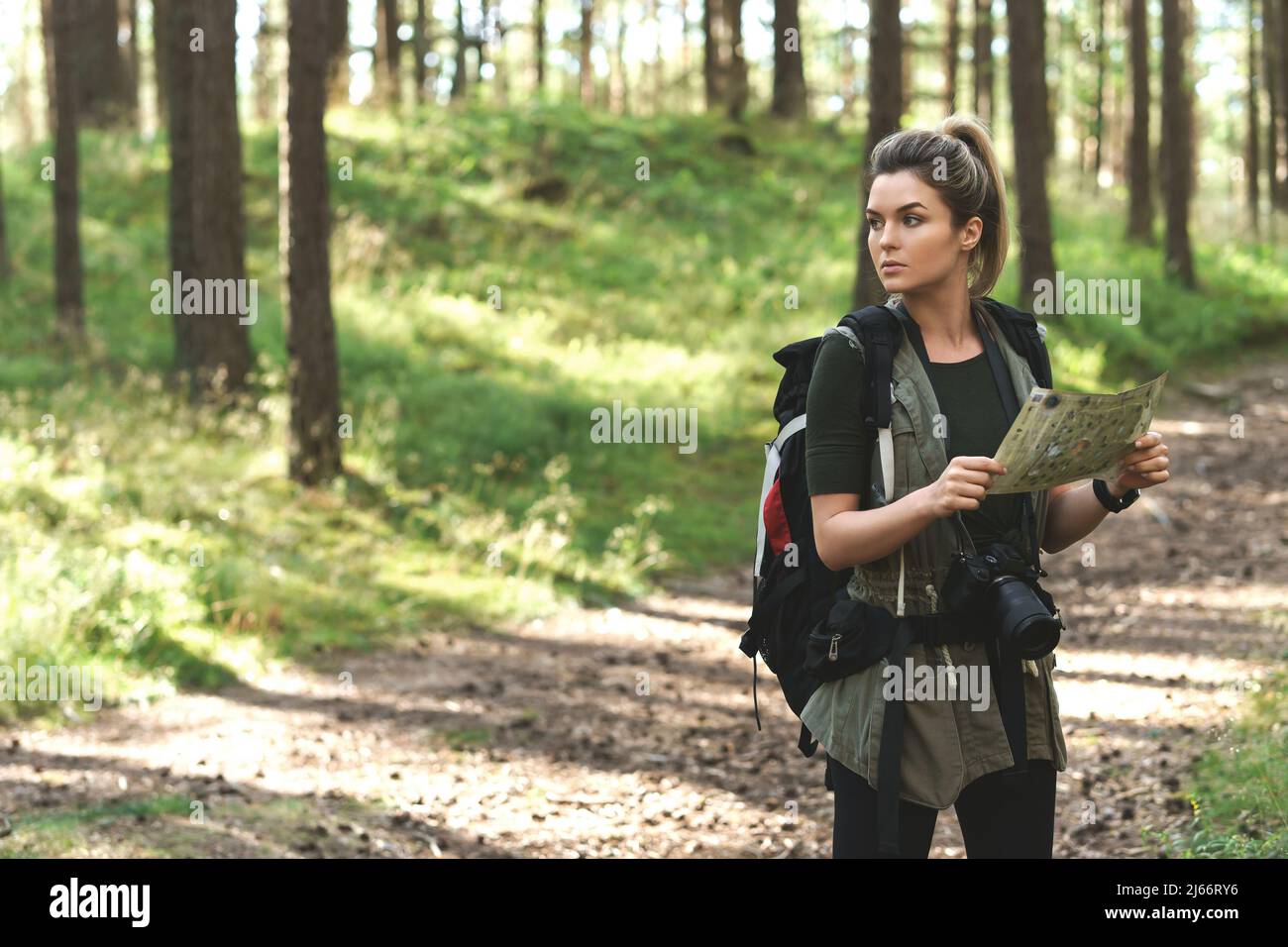 Female hiker with big backpack using map for orienteering in the forest ...