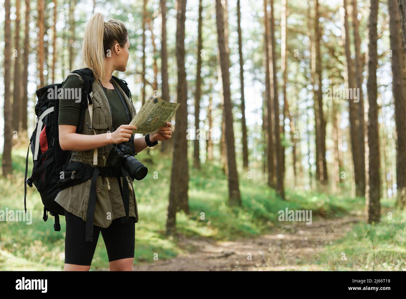 Female hiker with big backpack using map for orienteering in the forest ...