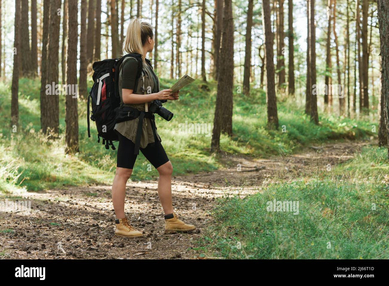 Female hiker with big backpack using map for orienteering in the forest ...