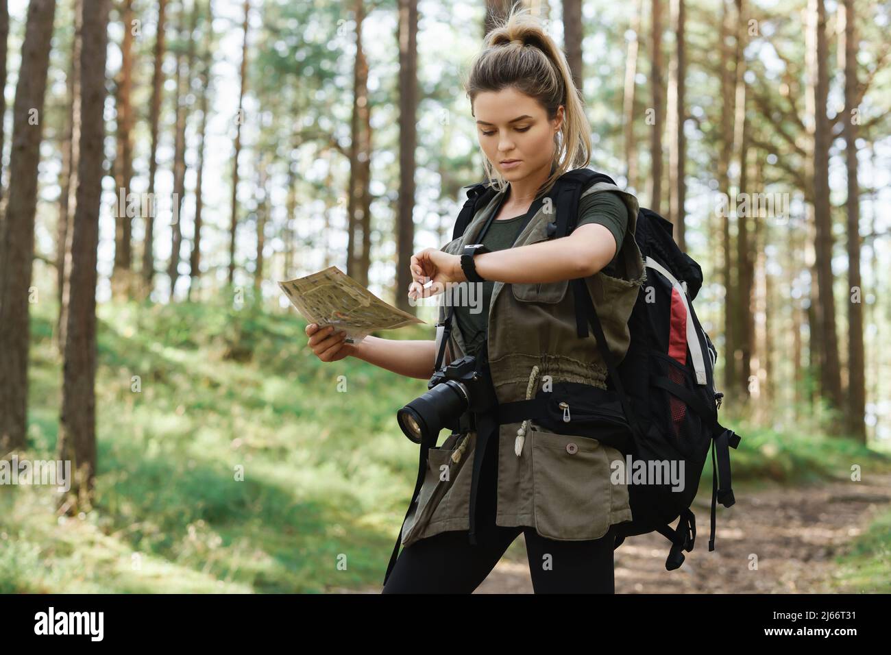 Female hiker with big backpack using map for orienteering in the forest ...
