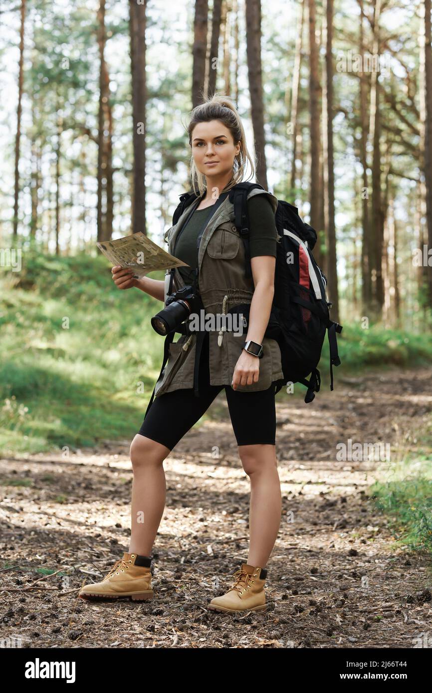Female hiker with big backpack using map for orienteering in the forest ...