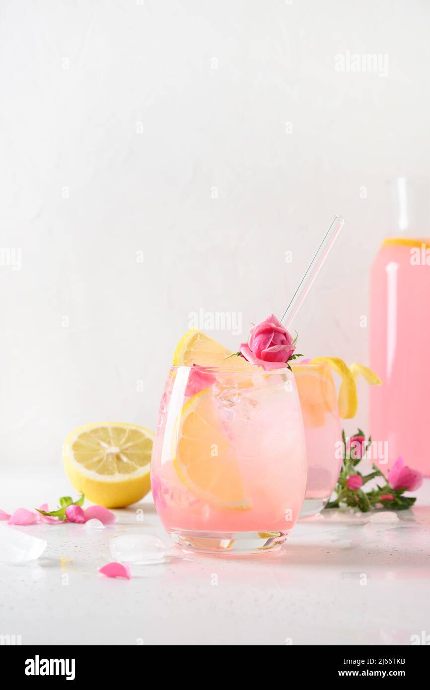 Pink alcoholic rose beverage or lemonade, cocktail with rose flowers on ...