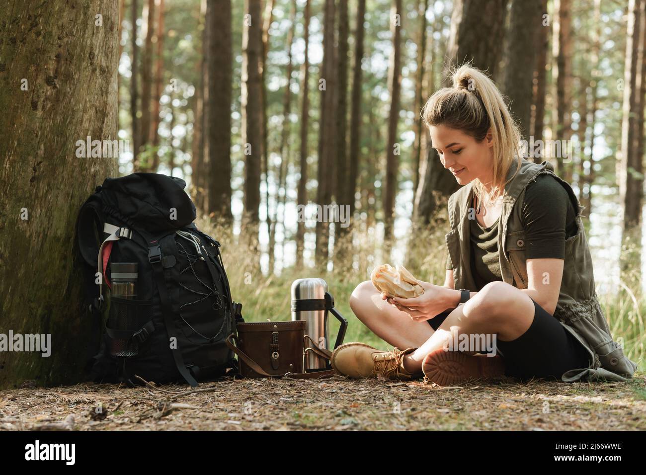 Female hiker during small halt eating sandwich in green forest Stock ...