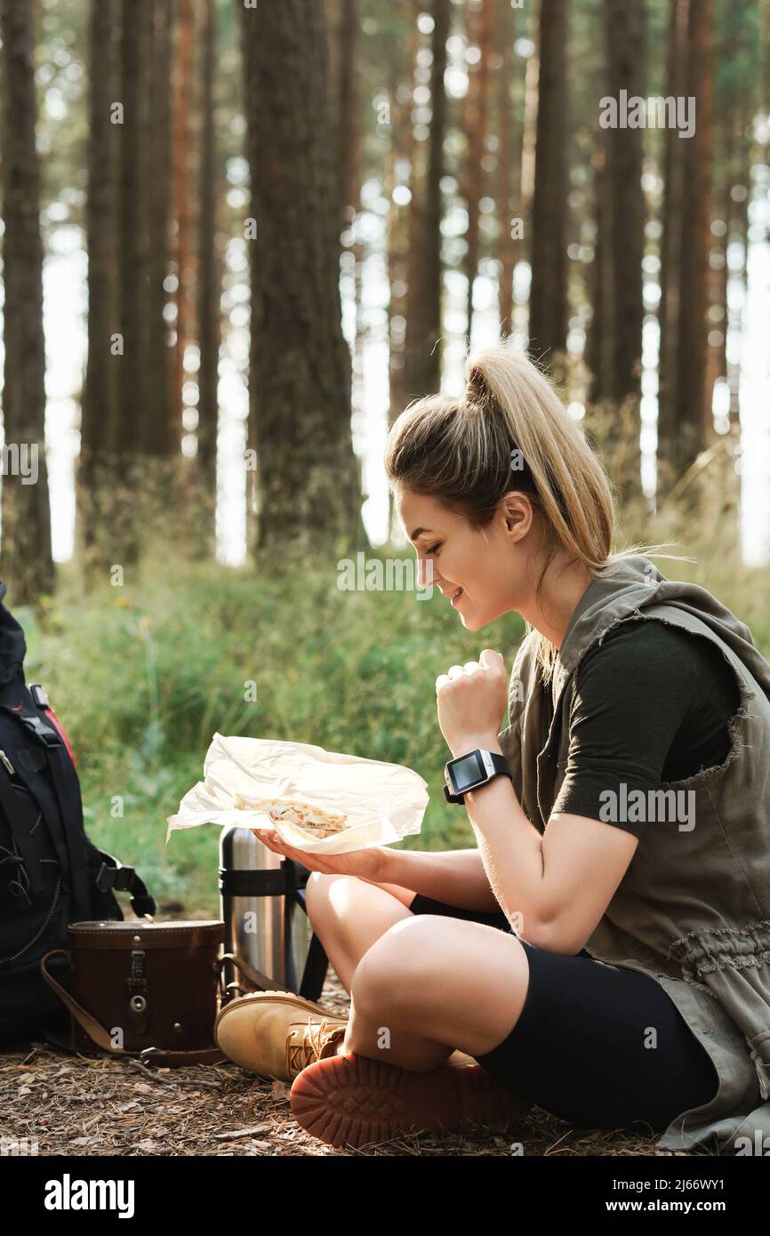 Female hiker during small halt eating sandwich in green forest Stock ...