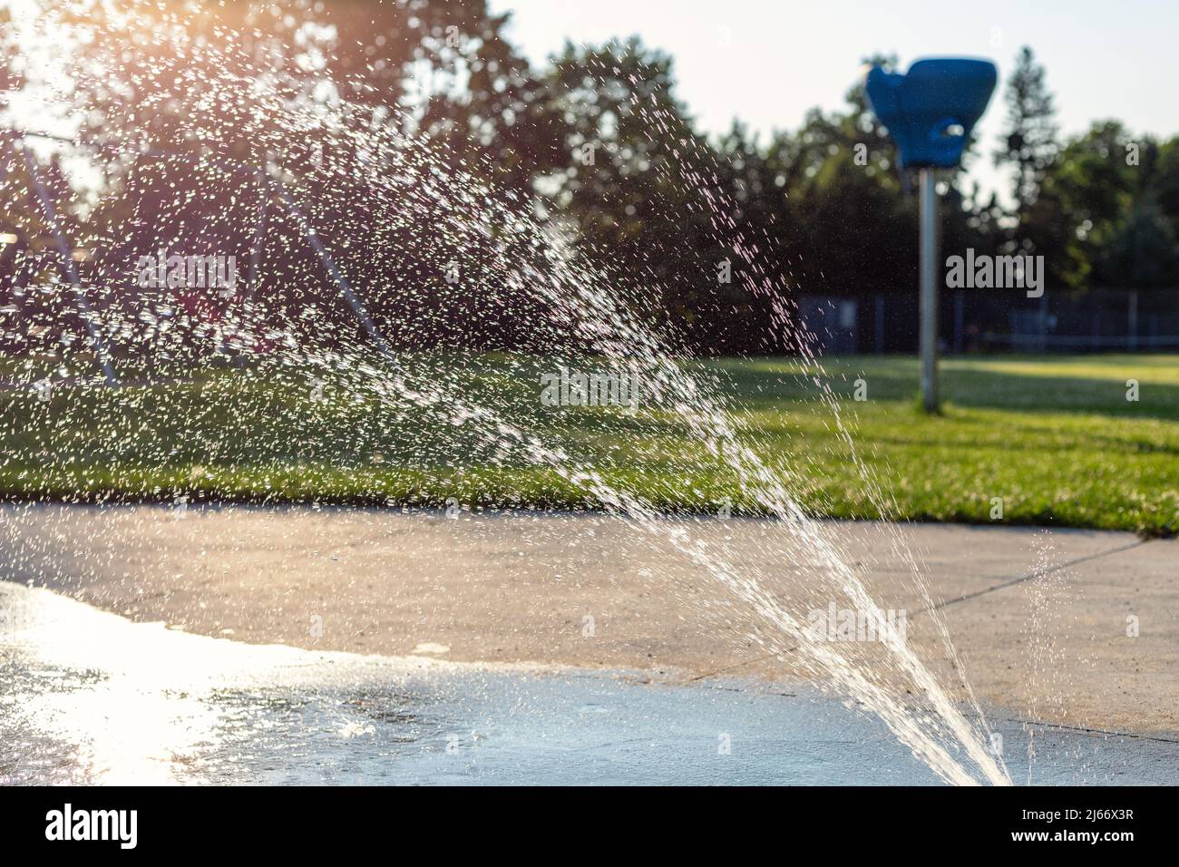 Splash pad playground in public park in summer without people. Fountain with splashing water on ...