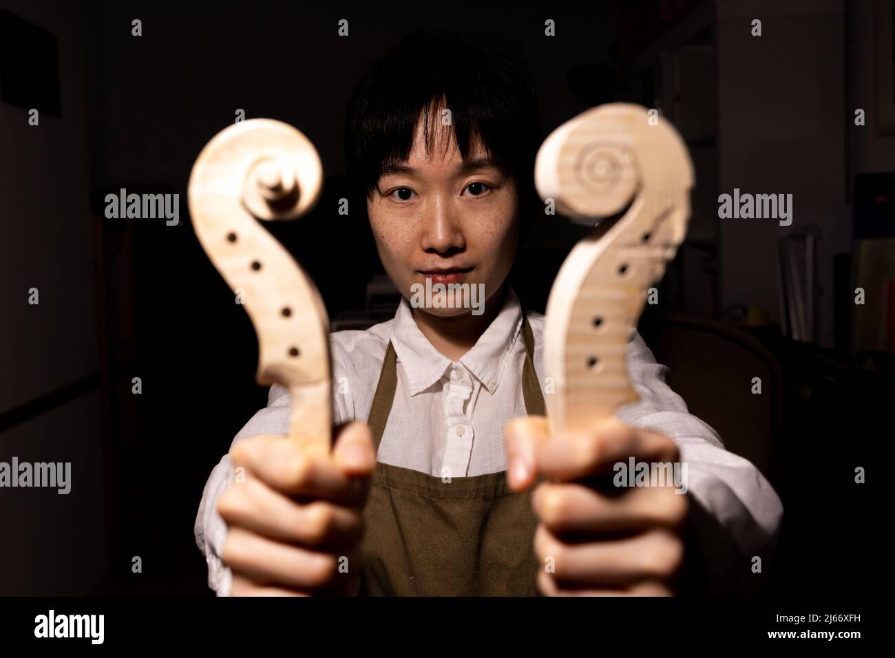 young chinese woman violin maker showing the neck of the violins under ...