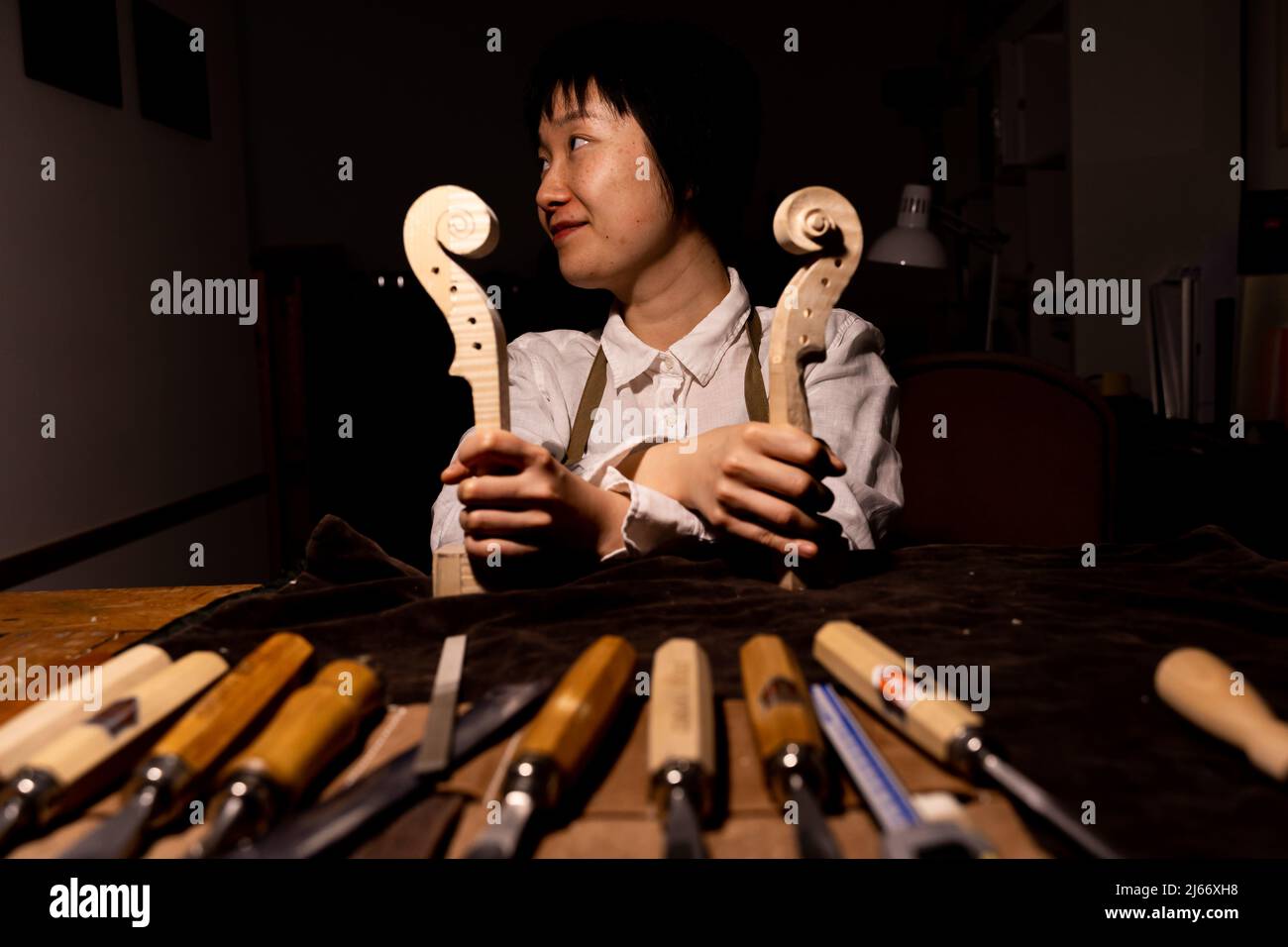 young chinese woman violin maker showing the neck of the violins under ...