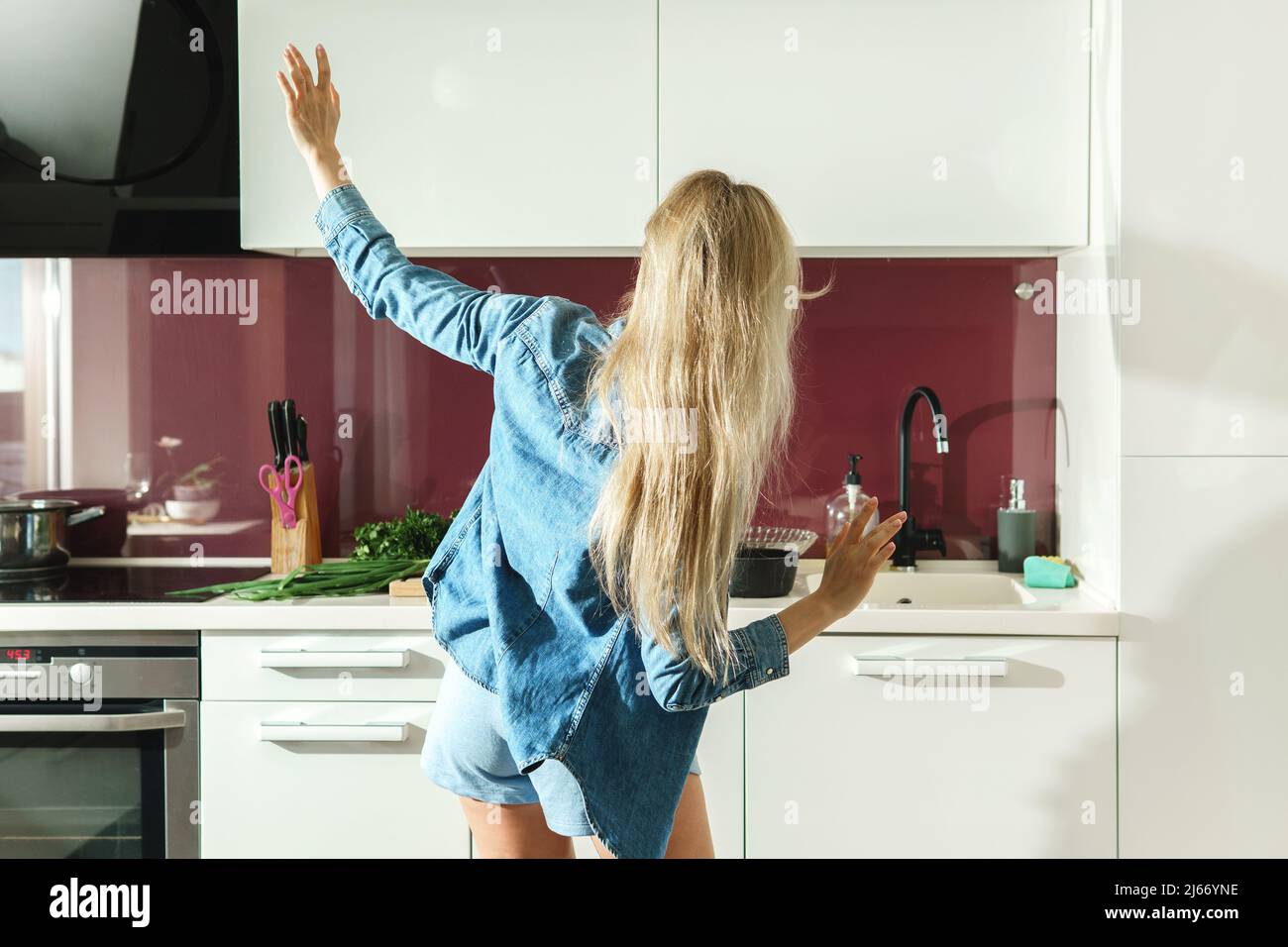 Attractive woman dancing on the kitchen while cooking during sunny ...