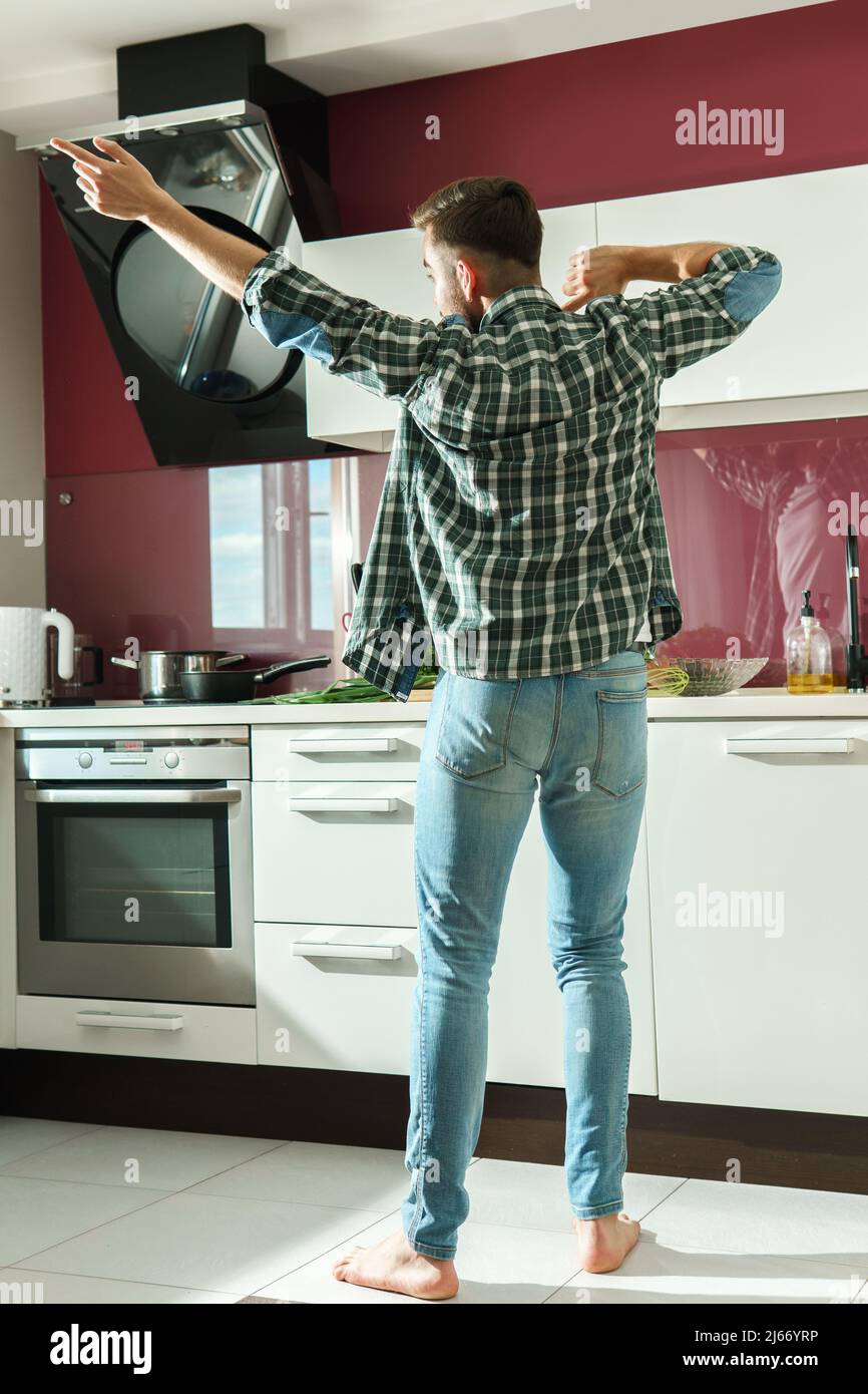 Handsome man dancing on the kitchen while cooking during sunny morning ...