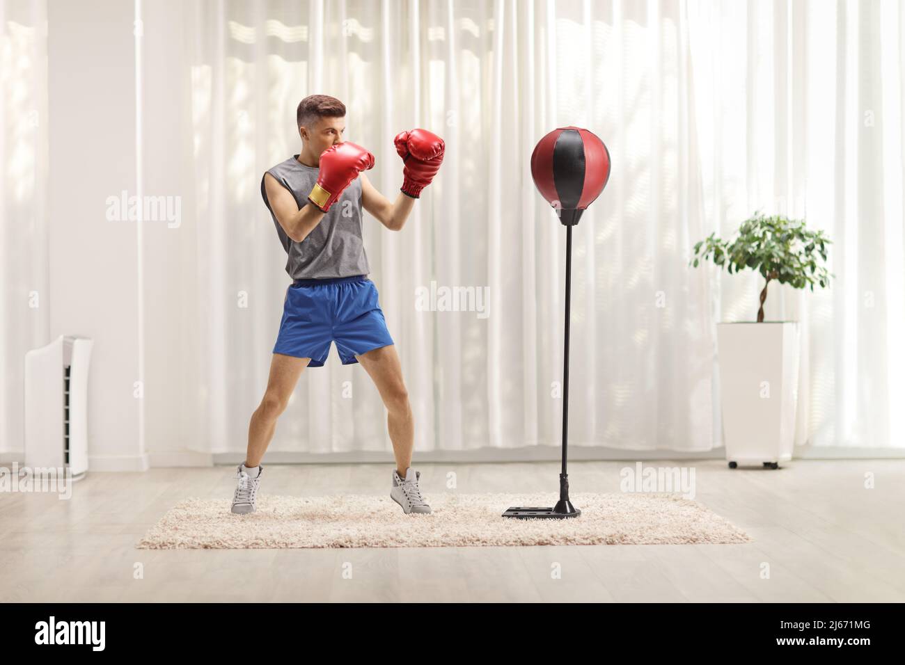 Full length shot of a young man training box with a free stand punch ...