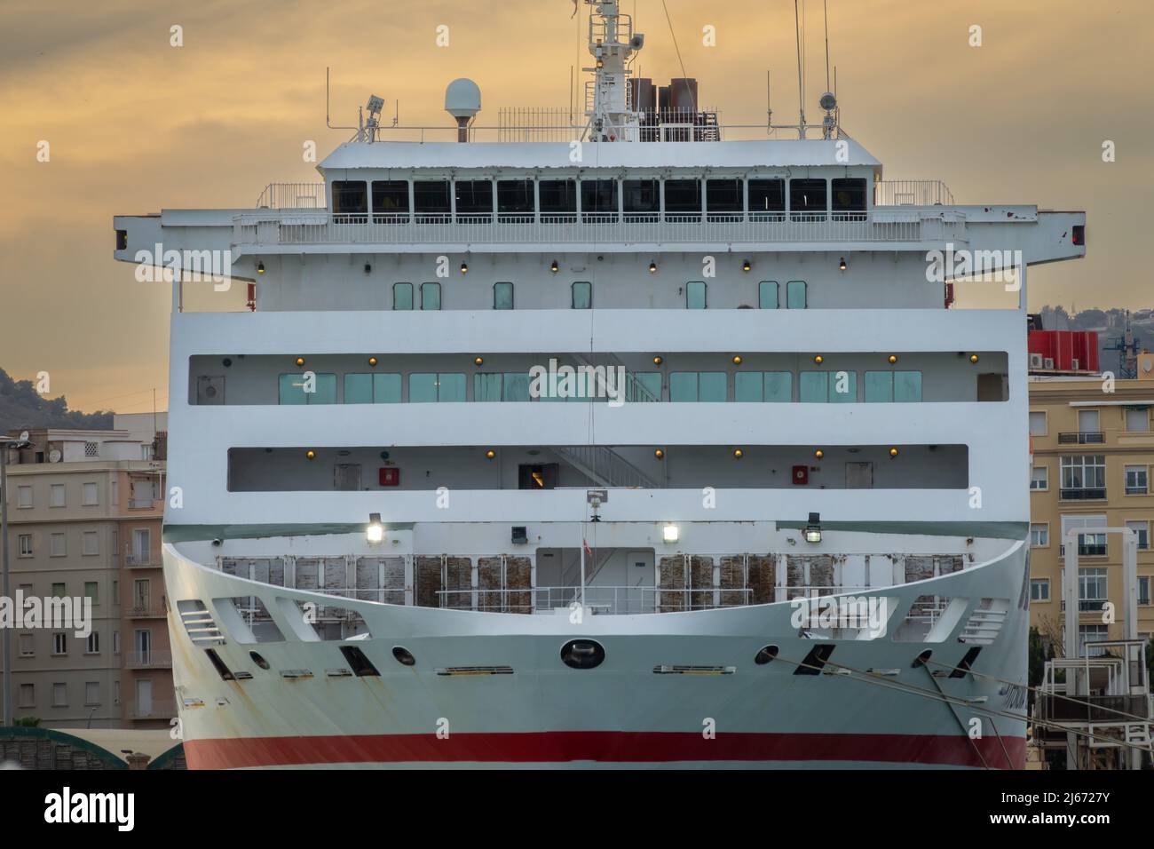 Front view of a large passenger ship at sunset with buildings in the ...