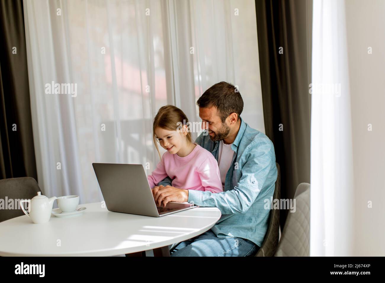 Father and daughter using laptop computer together in the room Stock ...