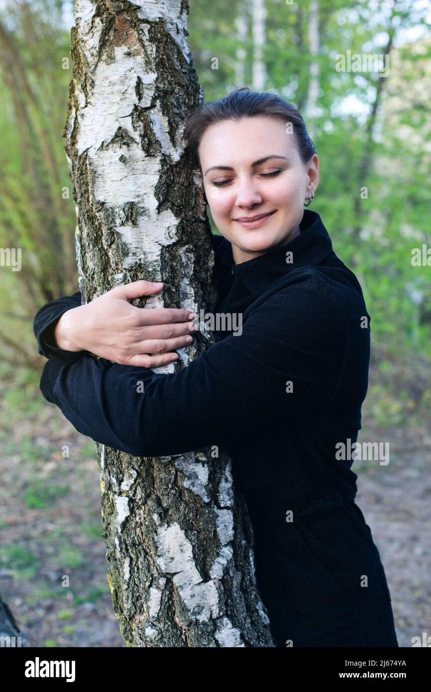 young brunette woman hugging a tree Stock Photo - Alamy