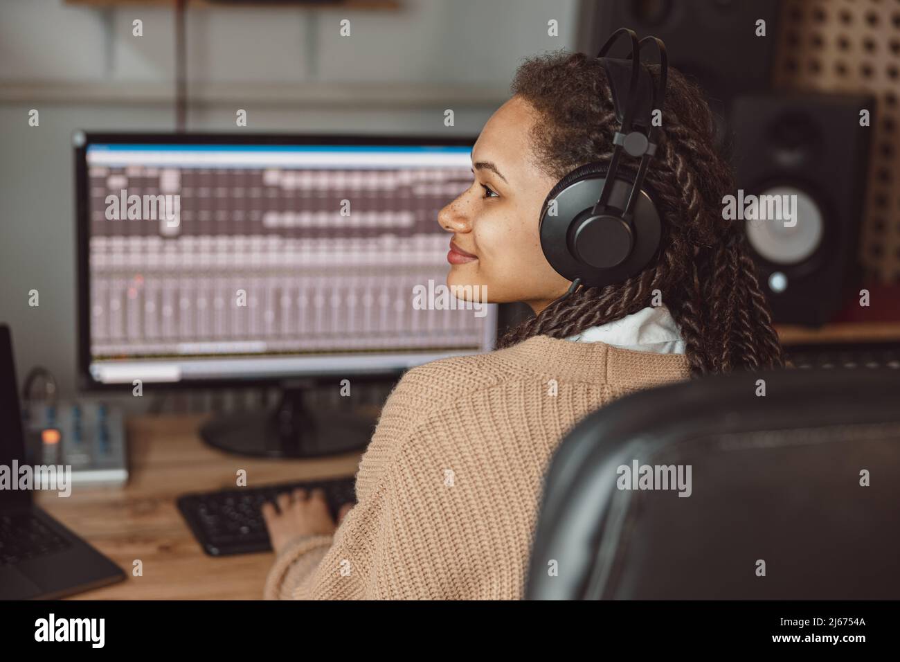 Sound engineer sits at desk with digital audio workstation software ...