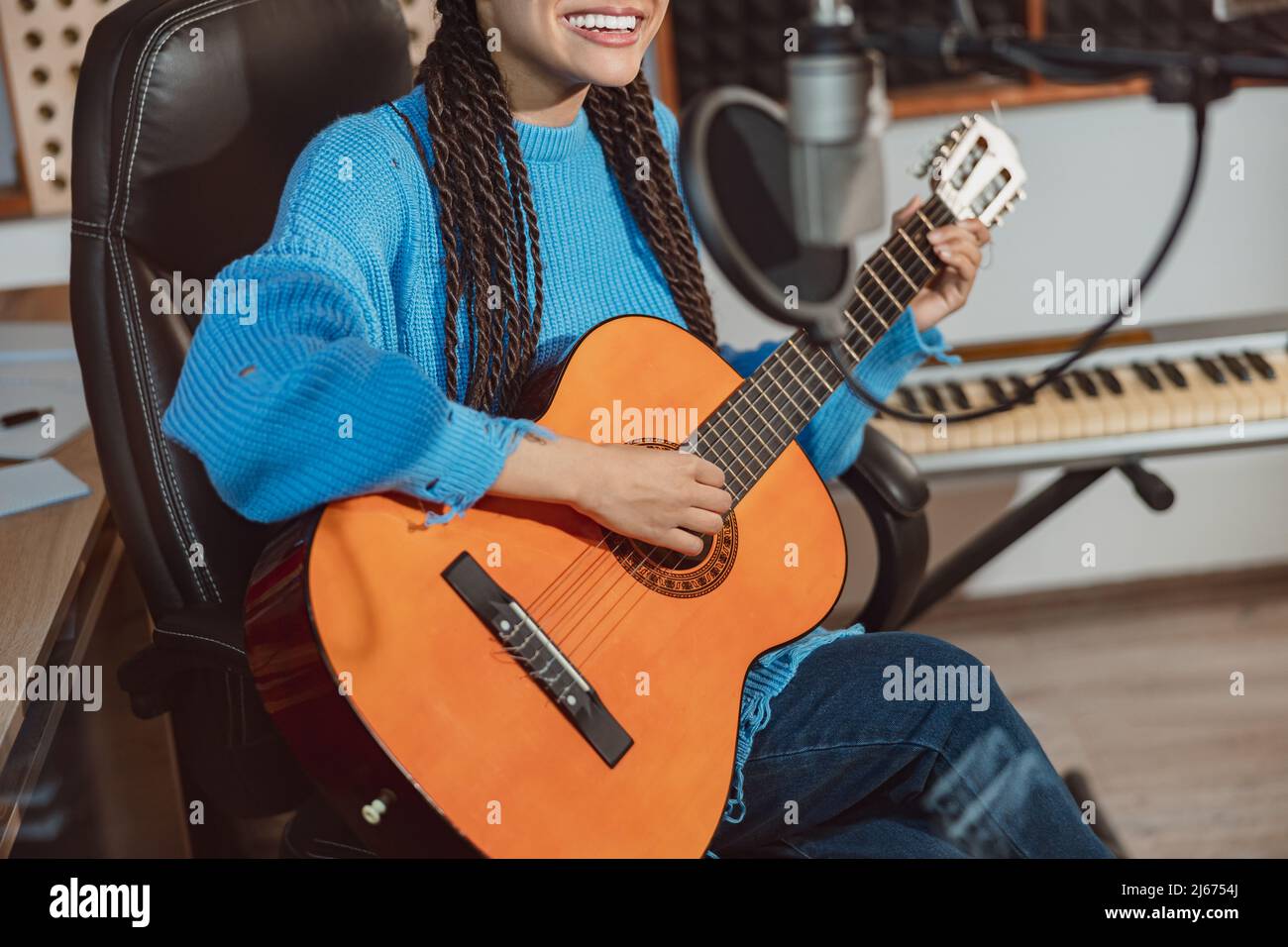 Focus on a guitar in the hands of a charming female musician playing ...