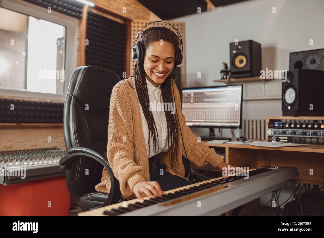 Stylish woman musician, sound composer playing synthesizer and ...