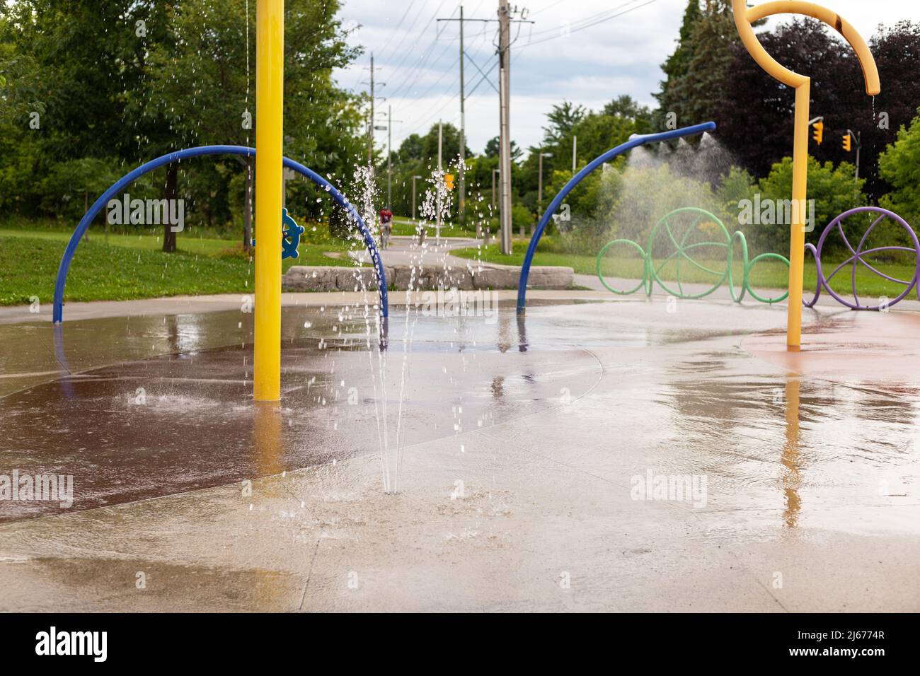 Splash pad playground in public park in summer without people. Fountains with splashing water on ...
