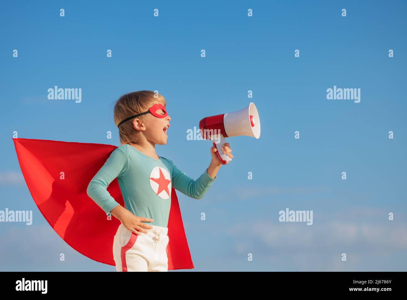 Superhero child shouting through loudspeaker outdoor. Super hero kid ...