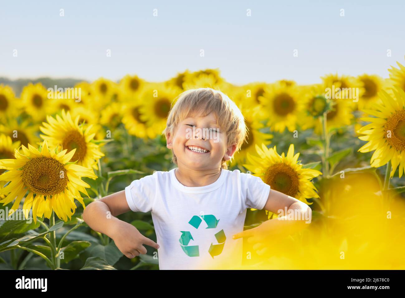 Happy child having fun in spring field of sunflowers. Outdoor portrait ...