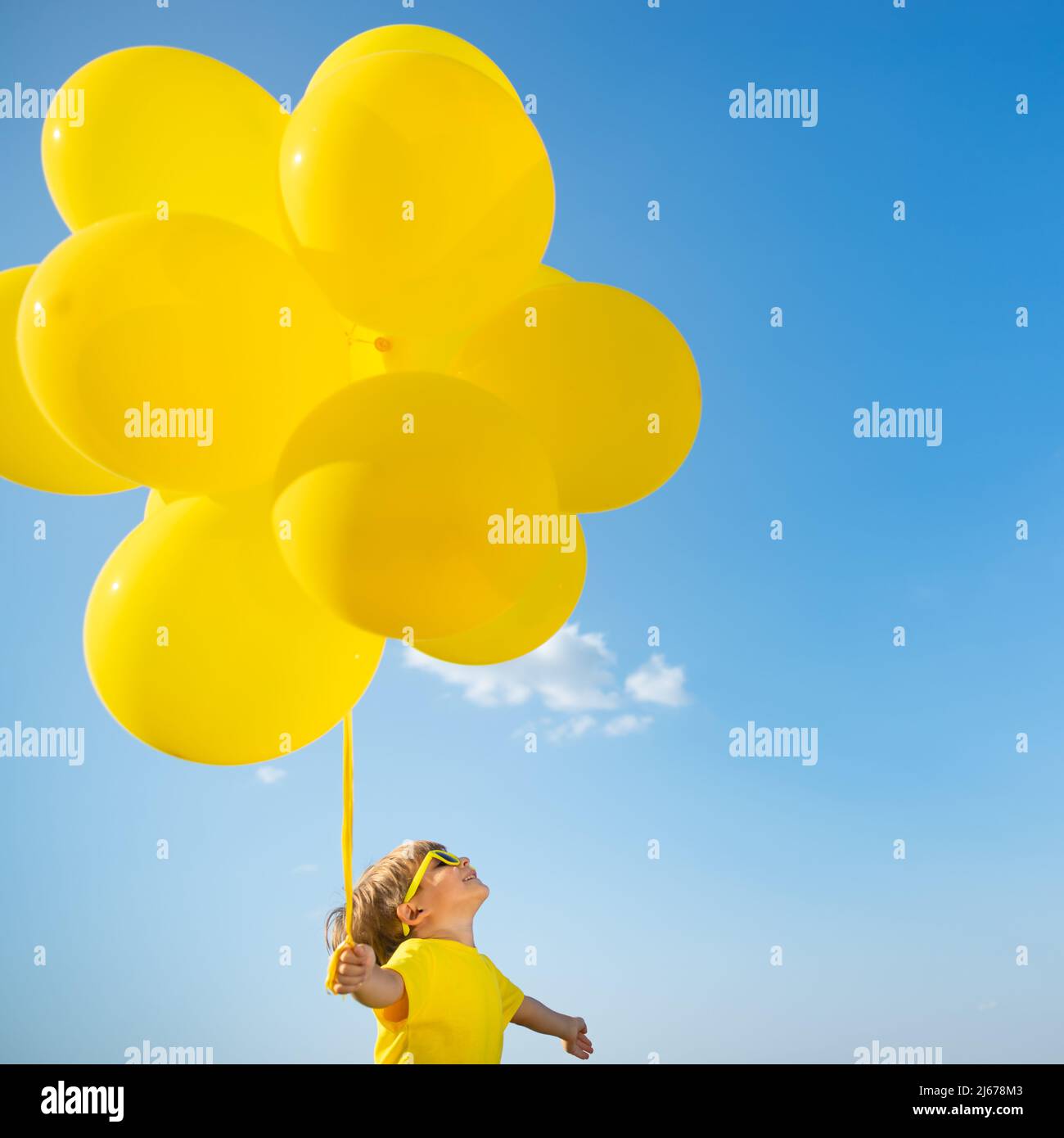 Happy child playing with yellow balloons outdoor. Kid having fun ...