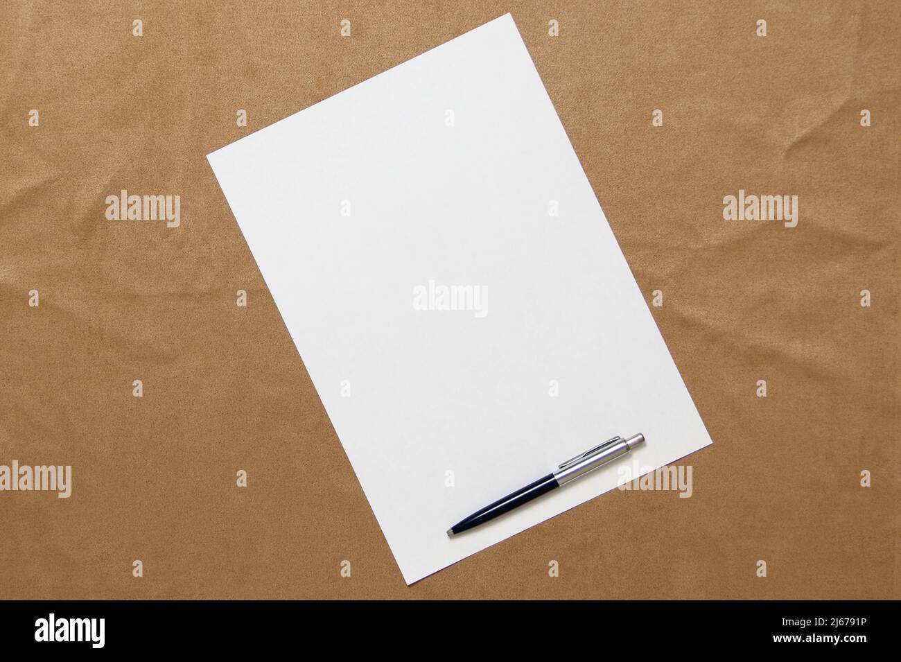 Template of white paper with pen lies diagonally on light brown cloth ...