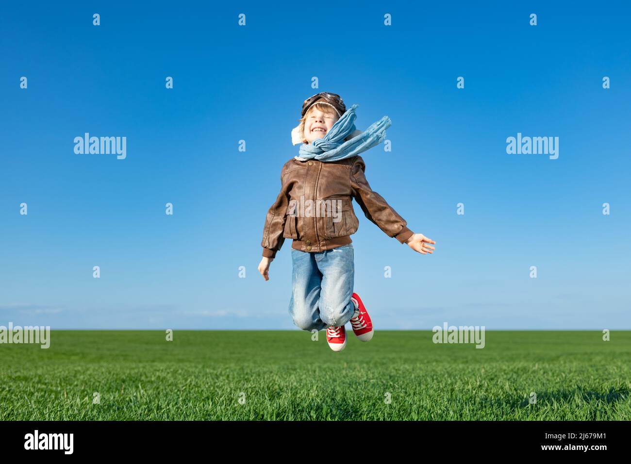 Happy child jumping outdoor in spring green field. Kid having fun ...