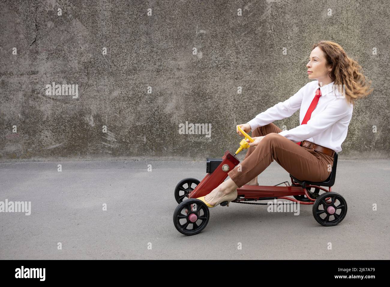 Portrait of funny businesswoman outdoor. Woman driving retro pedal car ...