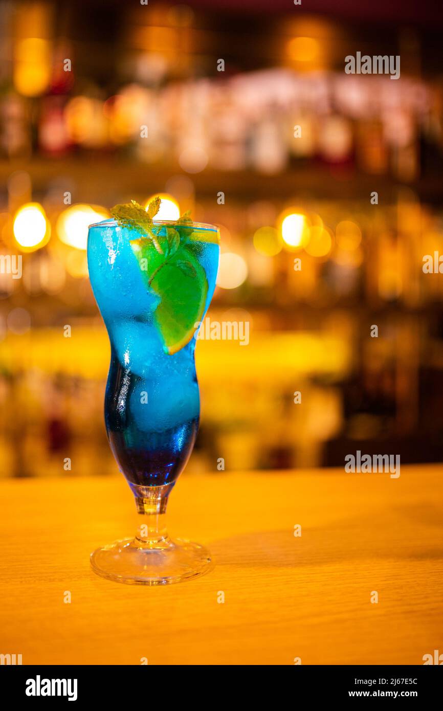 Blue alcoholic cocktail on the background of the bar, in a high glass ...